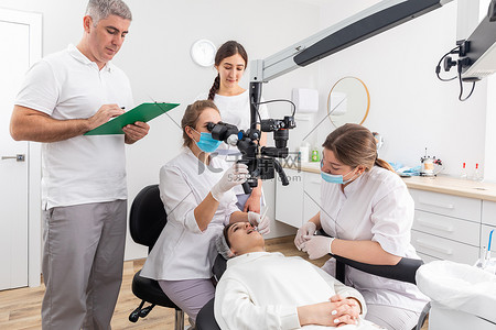 牙科诊所的一组学生学习用显微镜观察牙科治疗高清摄影大图-千库网