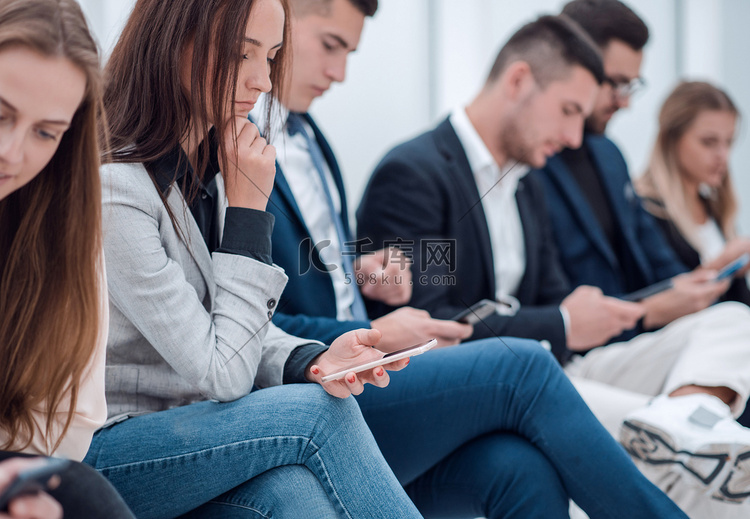 一群年轻人在排队等待，坐在队列中高清摄影大图-千库网