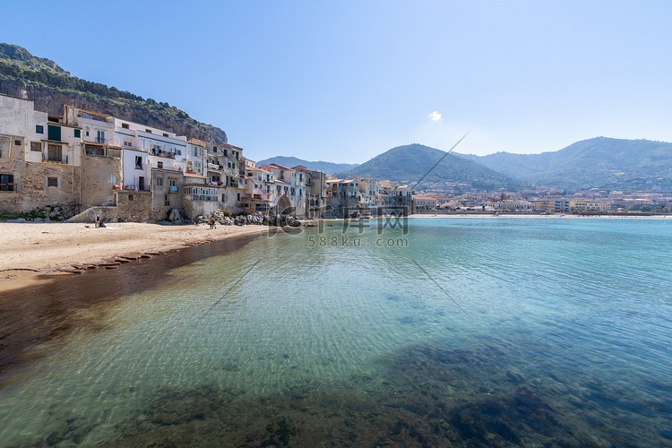 从意大利西西里岛切法卢历史悠久的老港口可以看到绿松石海的田园诗般的景色，以及以罗卡迪切法卢落基山为背景的房屋。高清摄影大图-千库网