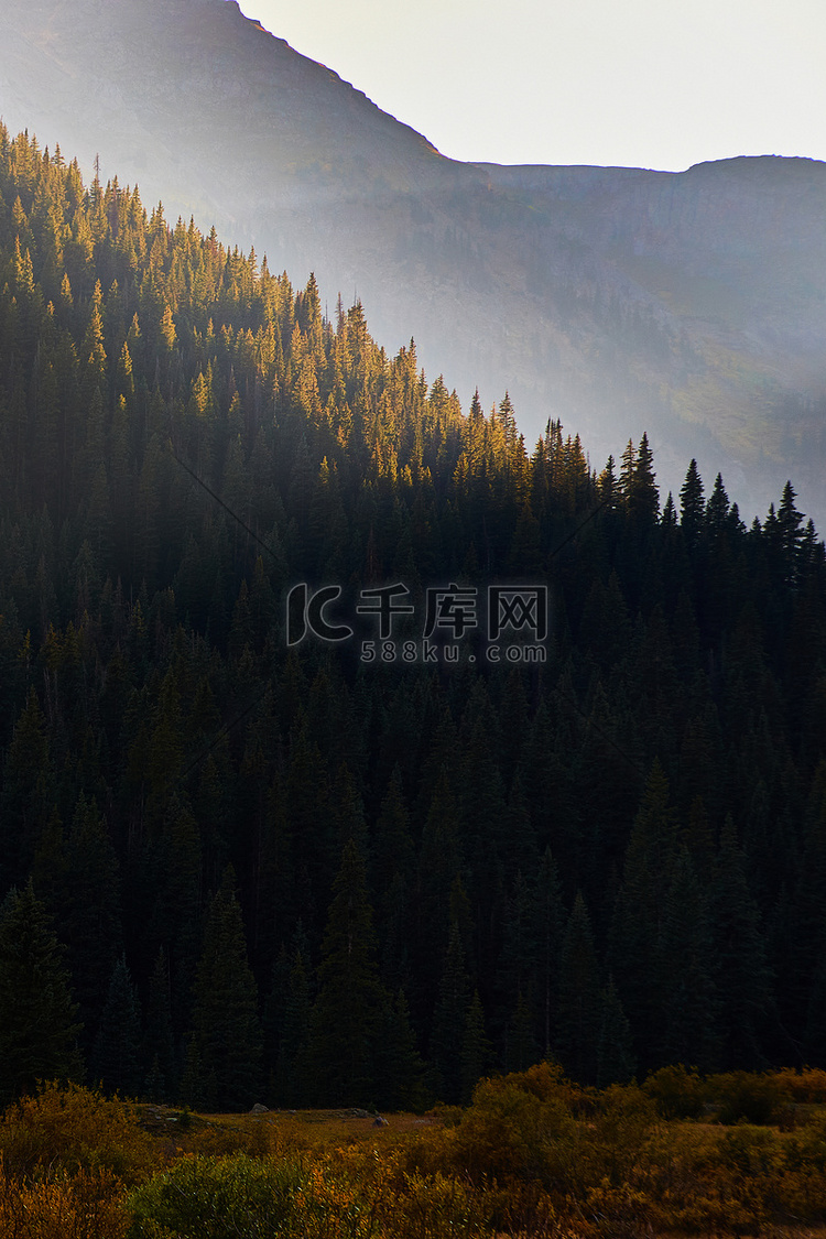 山上覆盖着松树，阳光照射在山峰上高清摄影大图-千库网