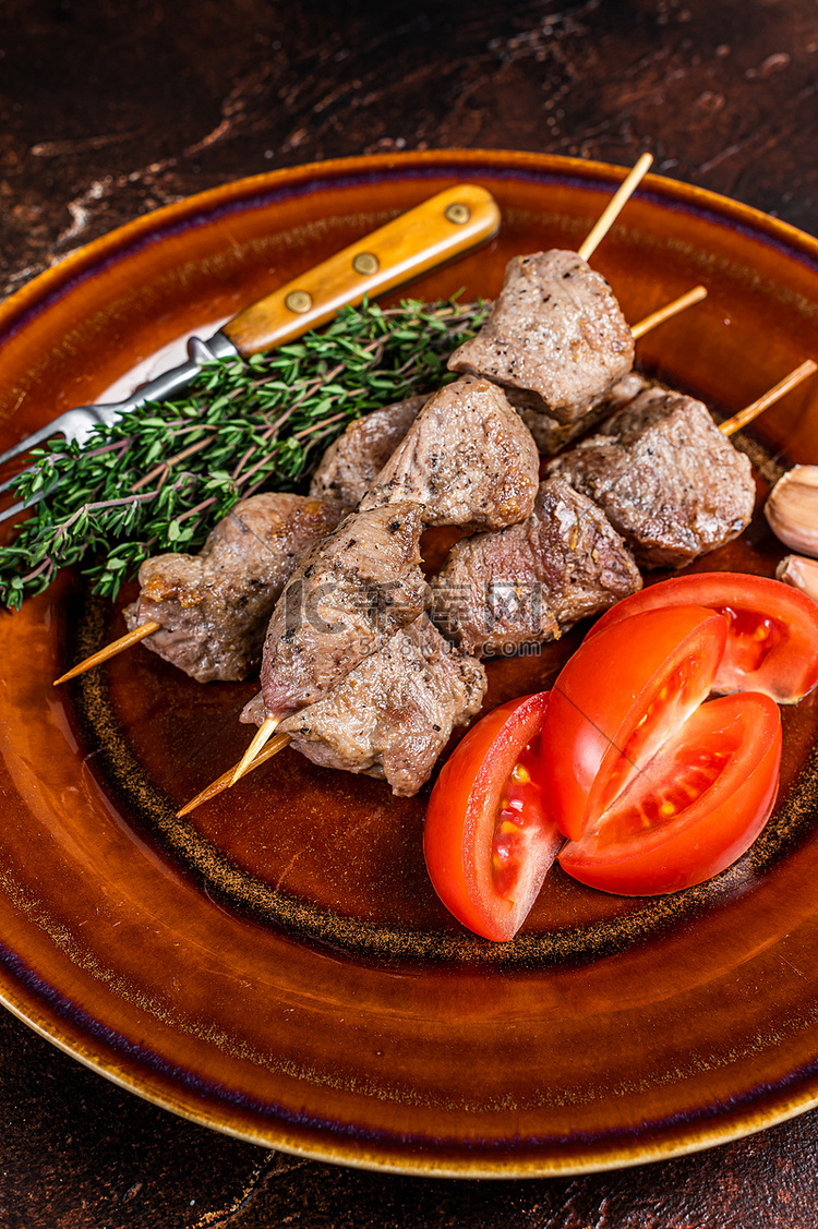 木串烧烤羊肉，质朴的盘子里放着蔬菜。高清摄影大图-千库网
