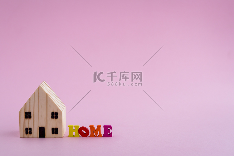 粉红色背景上带有 HOME 字母的木屋模型高清摄影大图-千库网
