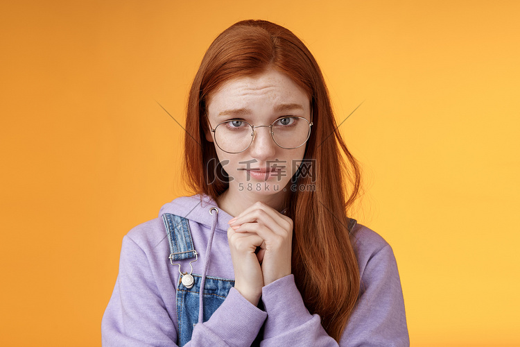 愚蠢而内疚的年轻害羞的红发女友请求宽恕,从额头下乞求低头的表情,皱着眉头乞求道歉,支持站立不安全的悲伤恳求帮助,橙色背景高清摄影大图 千库网