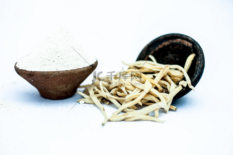 流行的印度和亚洲 ayurvedic 药草在粘土碗中以白色分离，即 Musli 或 safed musli 或 Chlorophytum ...