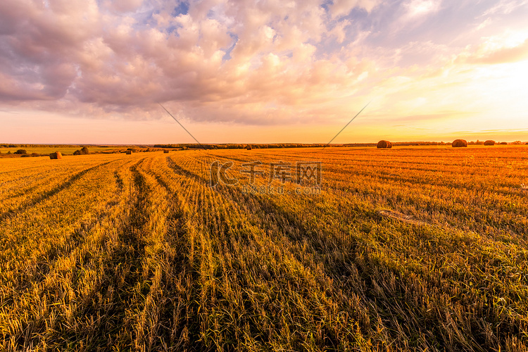 在秋天的季节，田野上的日落场景与干草堆。高清摄影大图-千库网