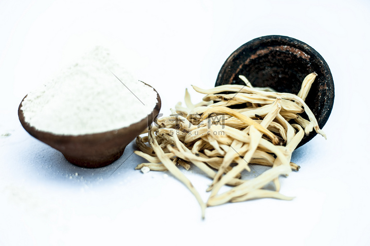 流行的印度和亚洲 ayurvedic 药草在粘土碗中以白色分离，即 Musli 或 safed musli 或 Chlorophytum ...