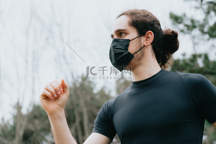 一名戴着面罩在公园跑步的年轻男性的特写高清摄影大图-千库网