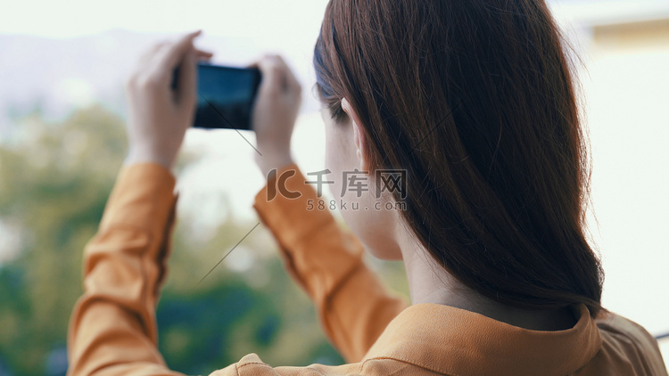 户外女人手里拿着手机在相机上拍照高清摄影大图-千库网