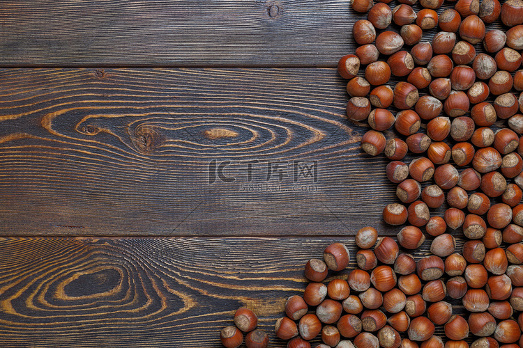 棕色木桌表面铺着带壳的榛子高清摄影大图-千库网
