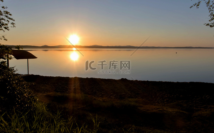 傍晚时分，金色的阳光洒落在湖面上高清摄影大图-千库网