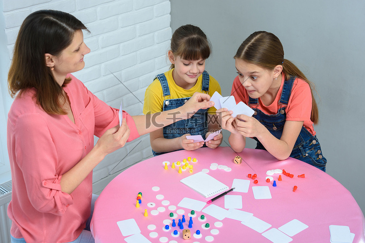 妈妈从女孩手中挑选一张卡片，女孩对这个选择感到惊讶高清摄影大图-千库网