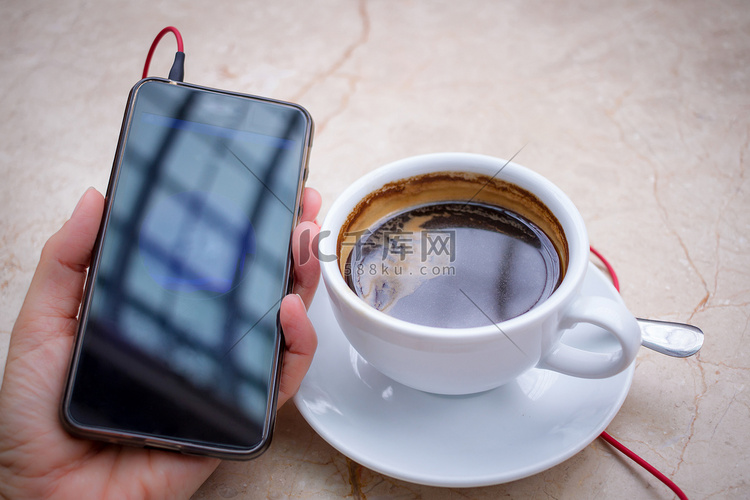 手边有红线的智能手机，桌上有美式咖啡高清摄影大图-千库网