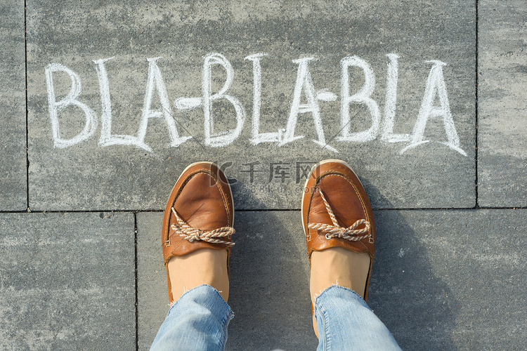 灰色人行道上写有“bla-bla-bla”文字的女性脚高清摄影大图-千库网