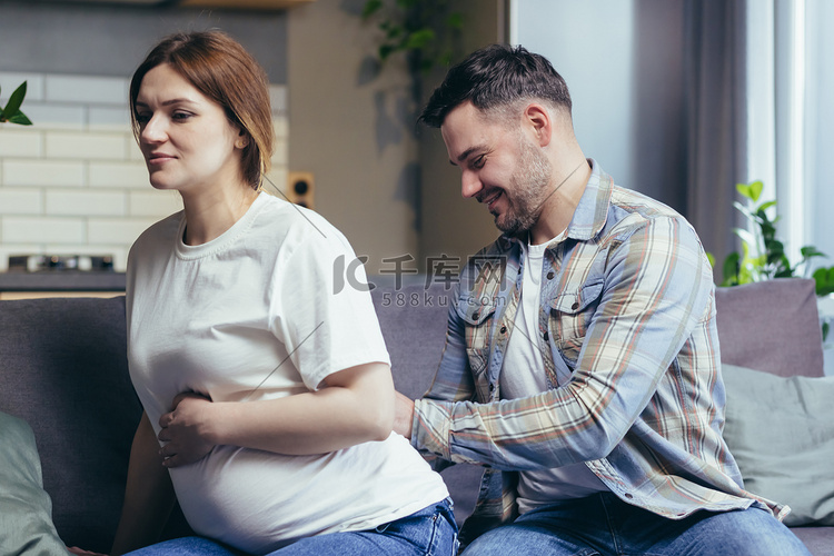 年轻夫妇坐在沙发上,丈夫按摩怀孕妻子的背部高清摄影大图 千库网