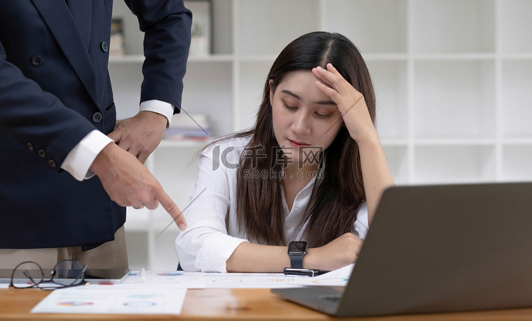 疲惫而无聊的年轻亚洲女商人或女办公室职员收到办公室男老板对她工作表现的抱怨。高清摄影大图-千库网