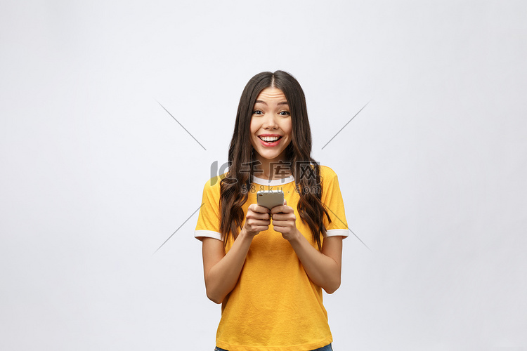 有魅力的亚洲少女看着手机屏幕，脸上带着喜悦的表情，白色背景上有复制空间。高清摄影大图-千库网