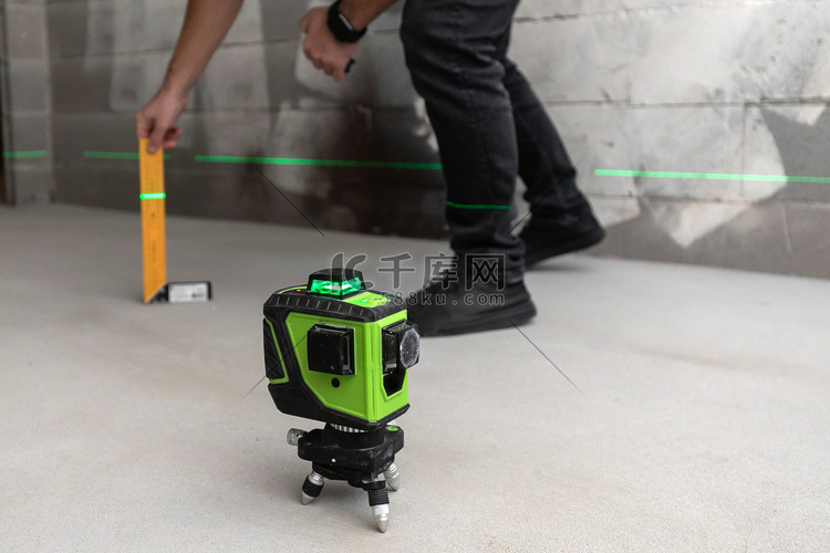 The worker inspector checks the floor level with a laser level meter ...