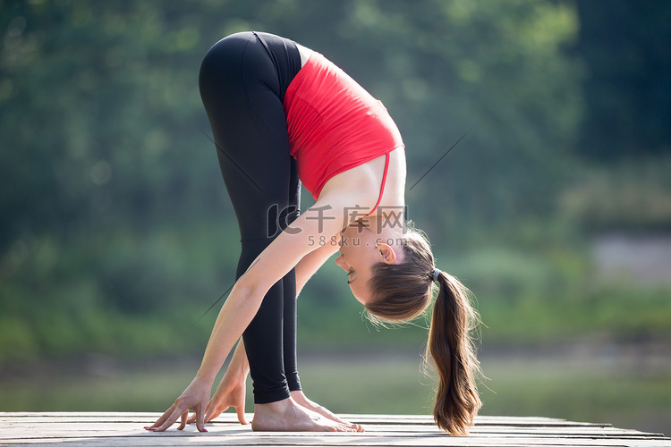 Teenage girl doing Standing Forward Bend Pose 高清摄影大图-千库网