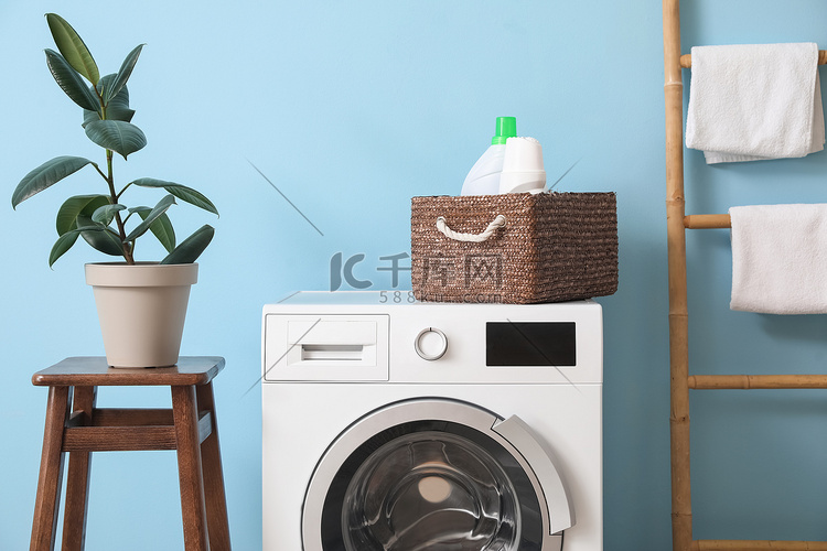 Washing machine with basket and detergent near blue wall in laundry ...