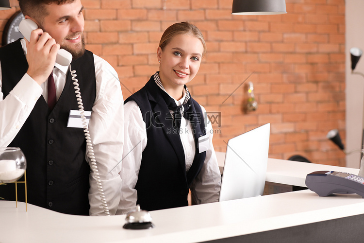 Male and female receptionists working at desk in hotel高清摄影大图-千库网