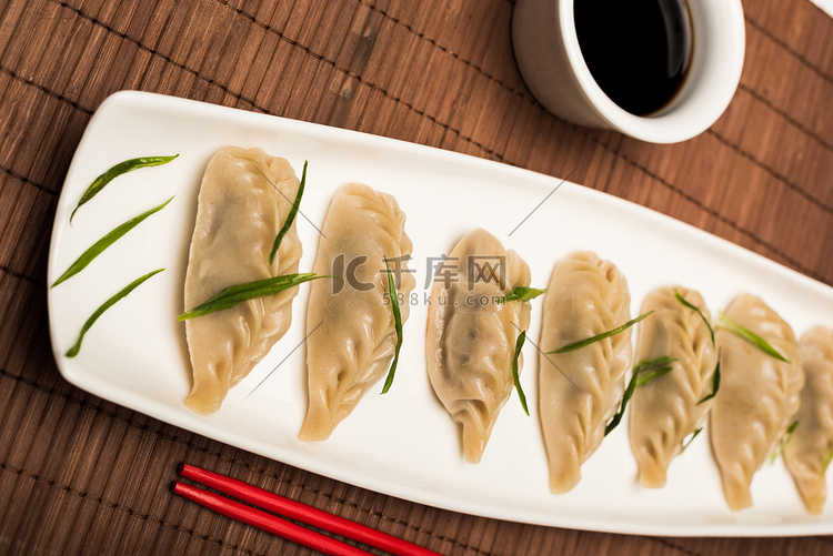 delicious Chinese boiled dumplings on plate near chopsticks and soy ...