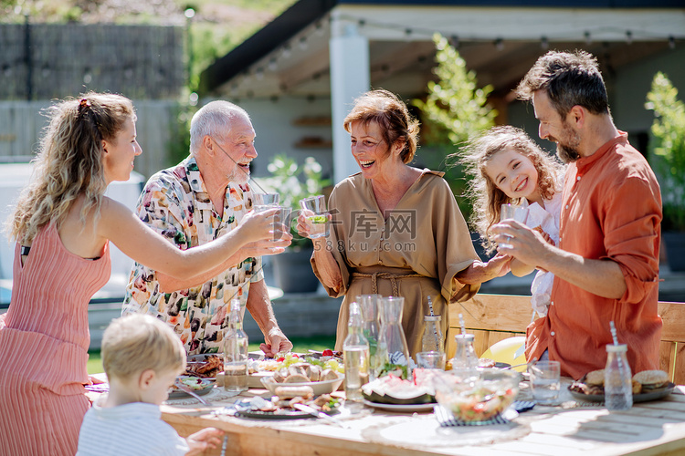 A multi generation family having garden party celebration, toasting and ...