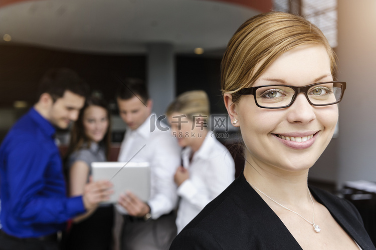 微笑的女商人在后台使用数字平板电脑的同事高清摄影大图-千库网