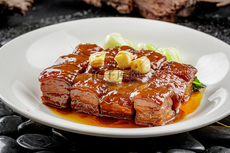白色圆盘装的毛氏红烧肉摆放在黑色鹅卵石上高清摄影大图-千库网