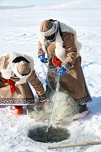 寒冷的冬季在冰冻的湖面上凿冰捕鱼的人们高清摄影大图-千库网