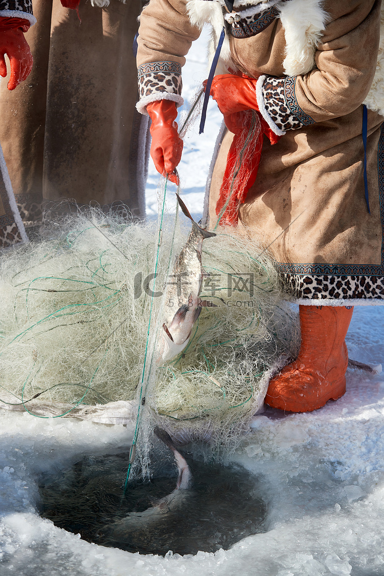 寒冷的冬季在冰冻的湖面上凿冰捕鱼的人们高清摄影大图-千库网