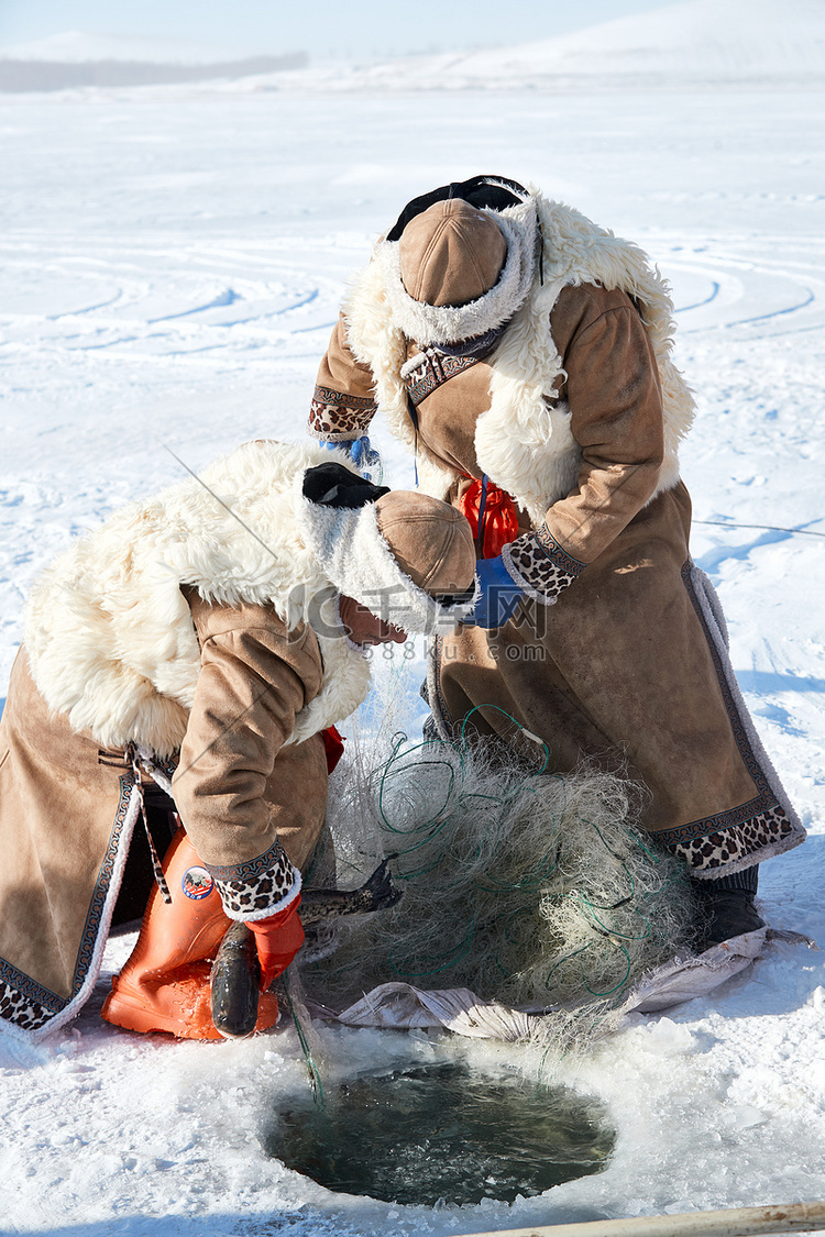 寒冷的冬季在冰冻的湖面上凿冰捕鱼的人们高清摄影大图-千库网
