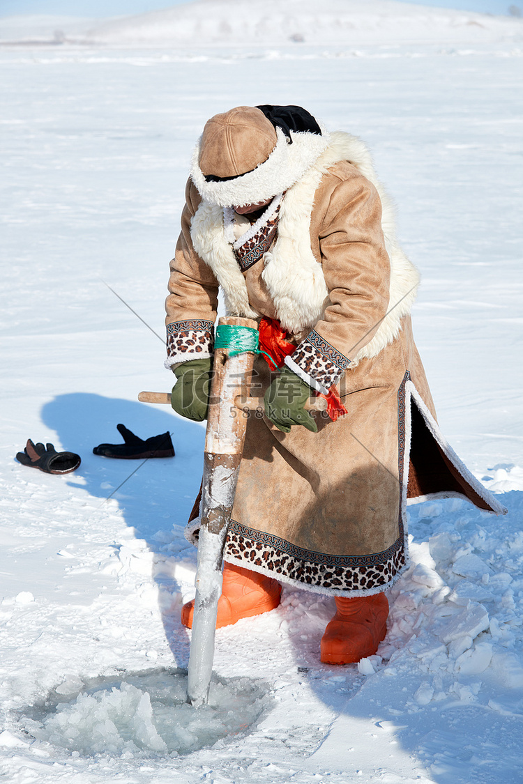 寒冷的冬季在冰冻的湖面上凿冰捕鱼的人们高清摄影大图-千库网