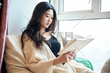 躺在舒适的飘窗上看书的女孩高清摄影大图-千库网