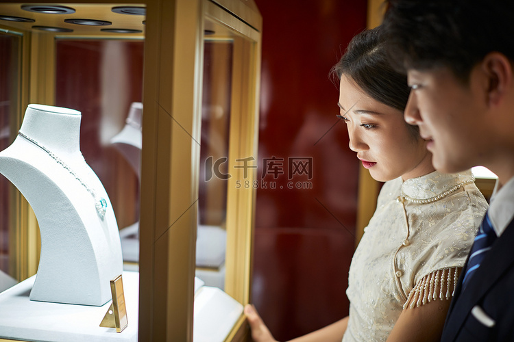 在珠宝店挑选石戒指的年轻情侣高清摄影大图-千库网