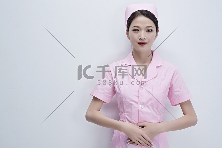 身穿粉色护士服佩戴听诊器的女性医护人员高清摄影大图-千库网
