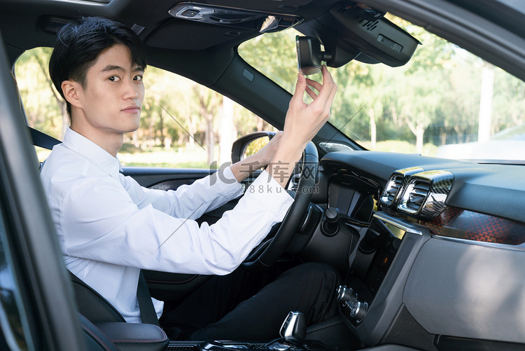 调整汽车内饰的青年男司机高清摄影大图-千库网