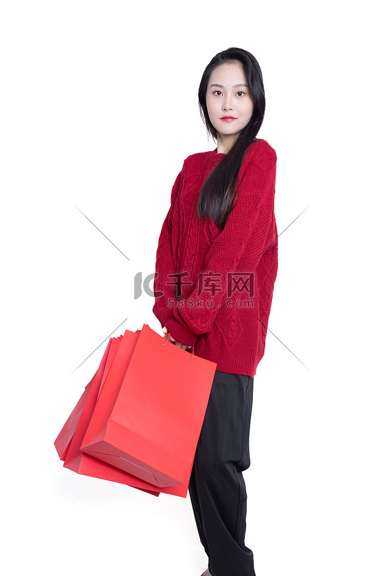 穿红色毛衣手持购物袋的年轻女性高清摄影大图-千库网