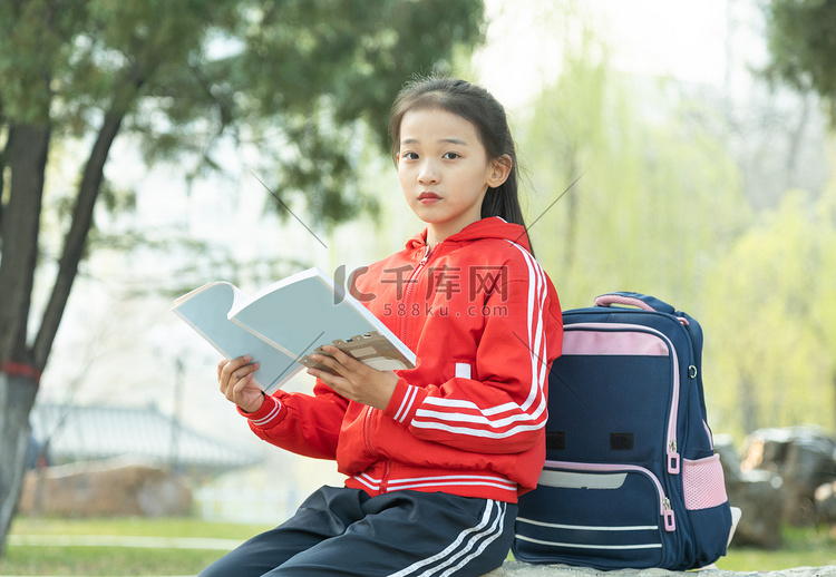 户外公园里认真读书的小学生高清摄影大图-千库网
