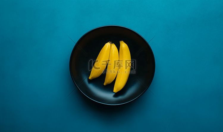 蓝色纹理表面黑盘中的香蕉果实高清摄影大图-千库网