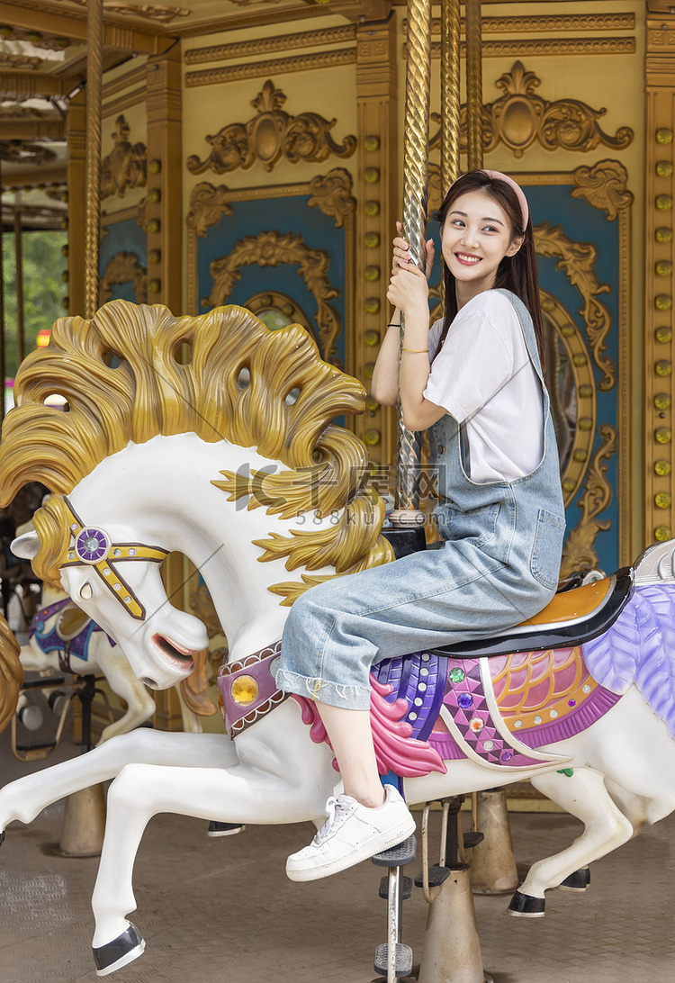 在游乐园里玩旋转木马的美丽东方女孩高清摄影大图-千库网