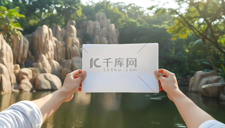 年轻人在宁静的自然公园的背景下展示一张白纸高清摄影大图-千库网